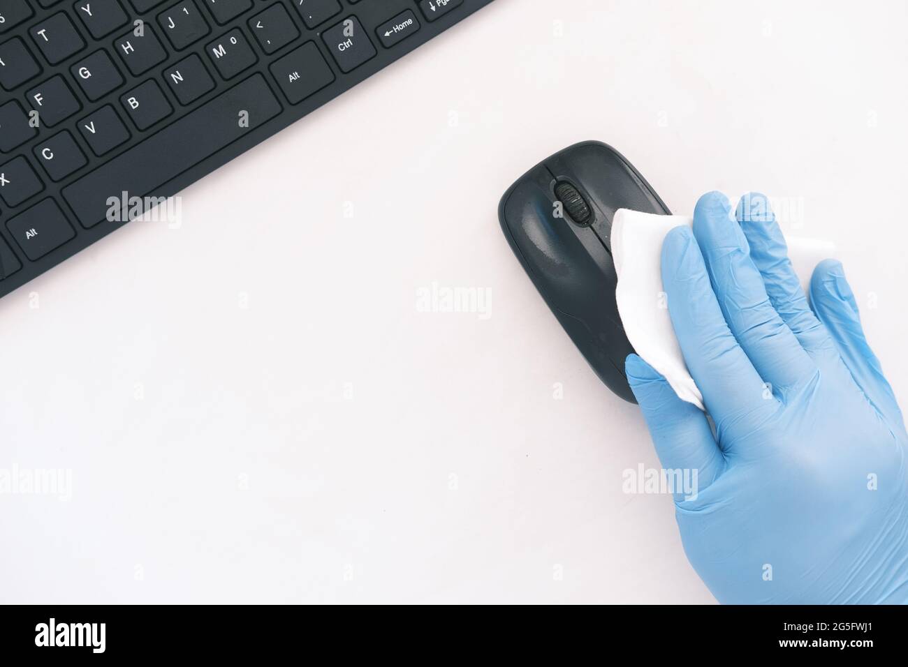 hand in blue rubber gloves and white tissue disinfecting computer mouse ...
