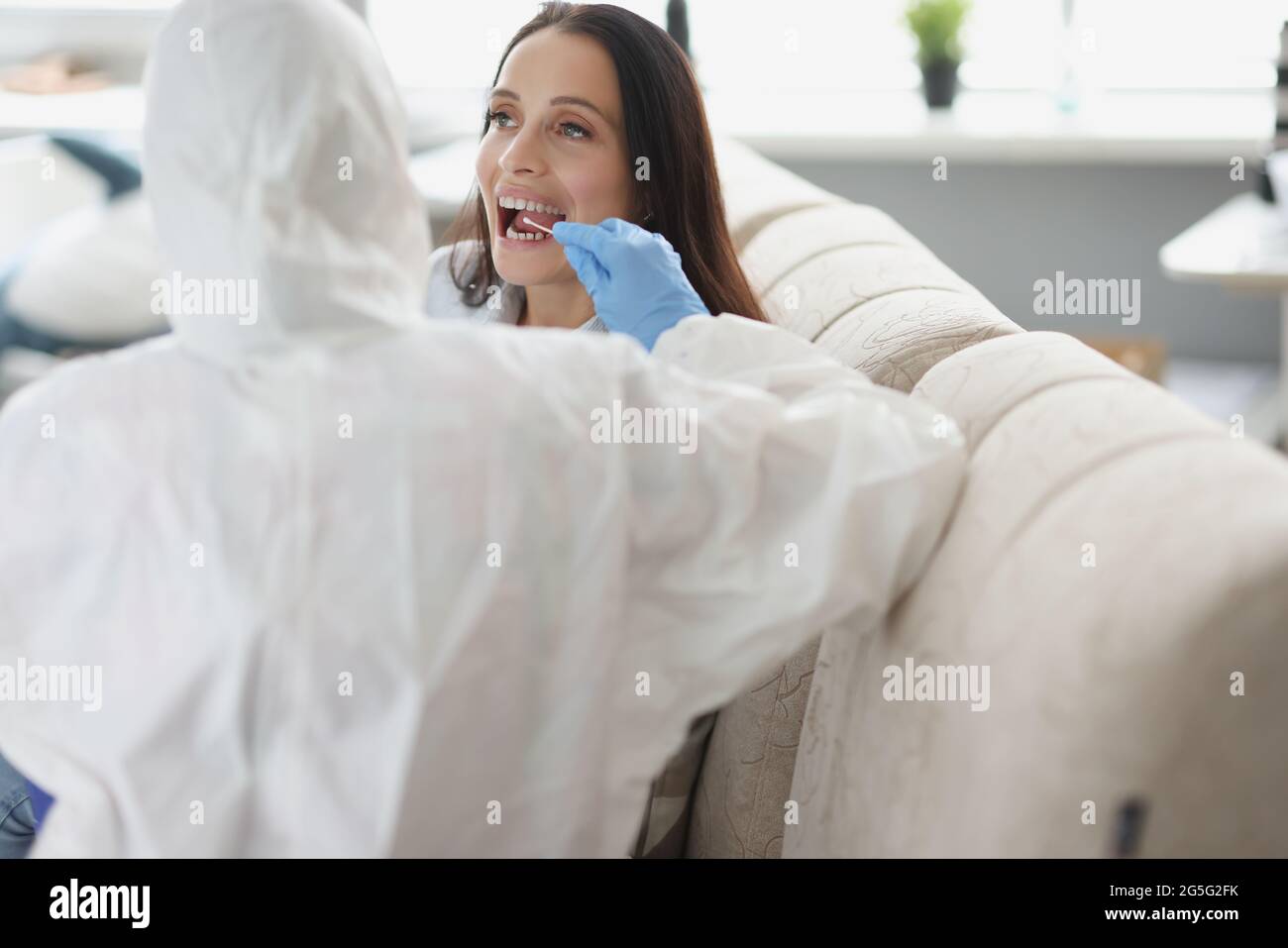 Doctor in a protective antiplague suit taking PCR smear to woman ...