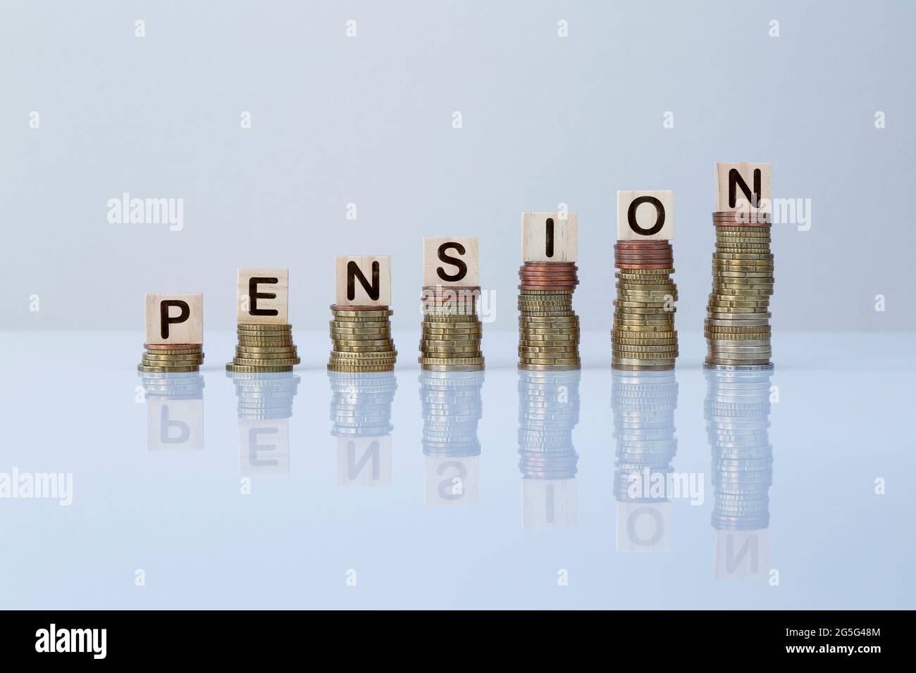 Word "PENSION" on wooden blocks on top of ascending stacks of coins on ...