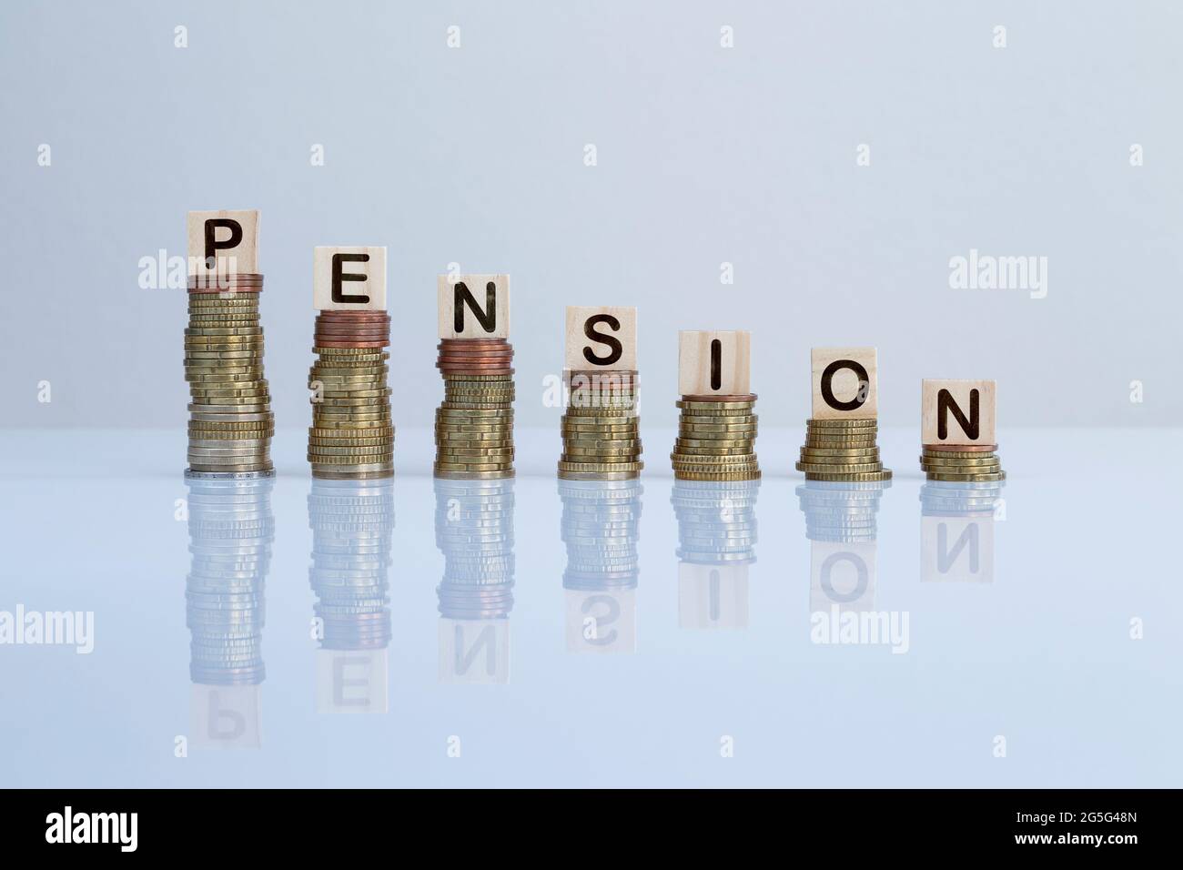 Word "PENSION" on wooden blocks on top of descending stacks of coins ...