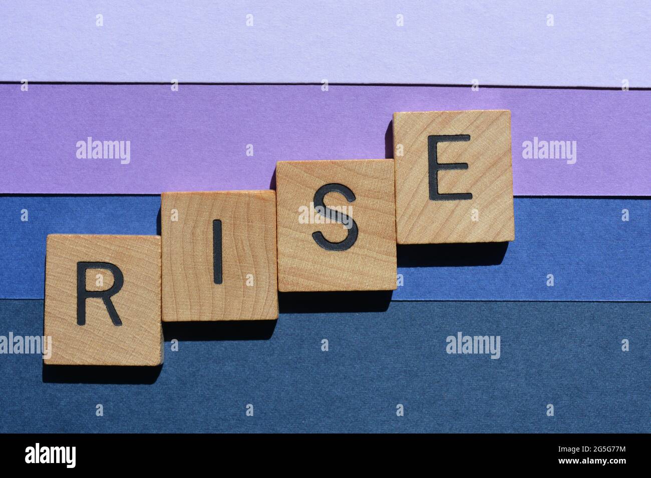 Rise, word in wooden alphabet letters isolated on blue and purple ...