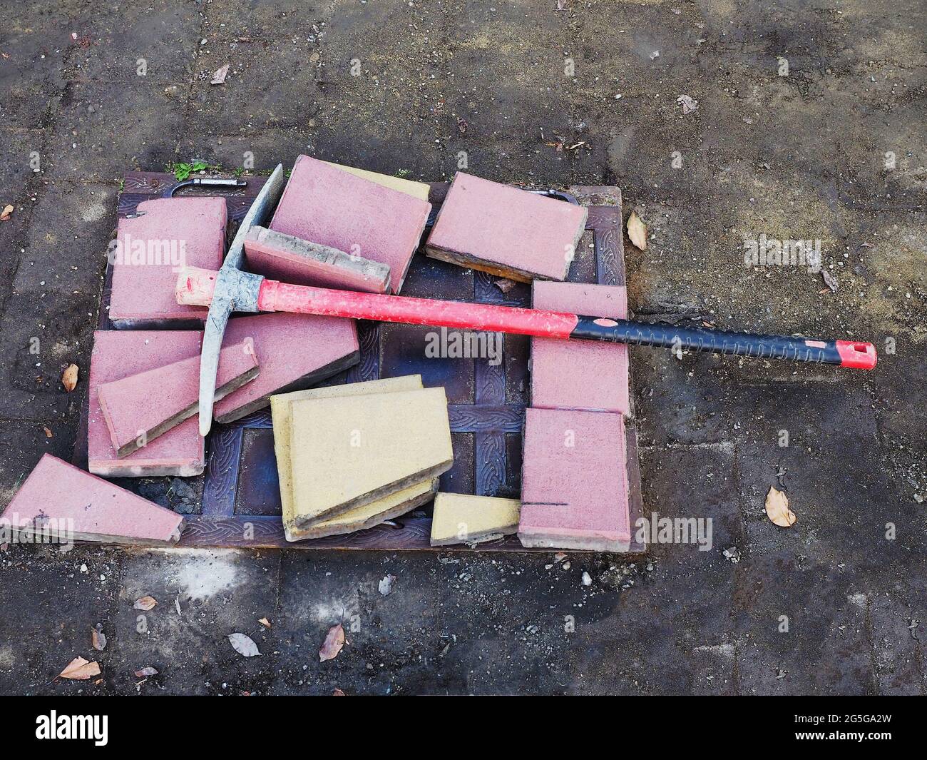 Pickaxe lies on the ground with pieces of paving slabs. Improvement of ...