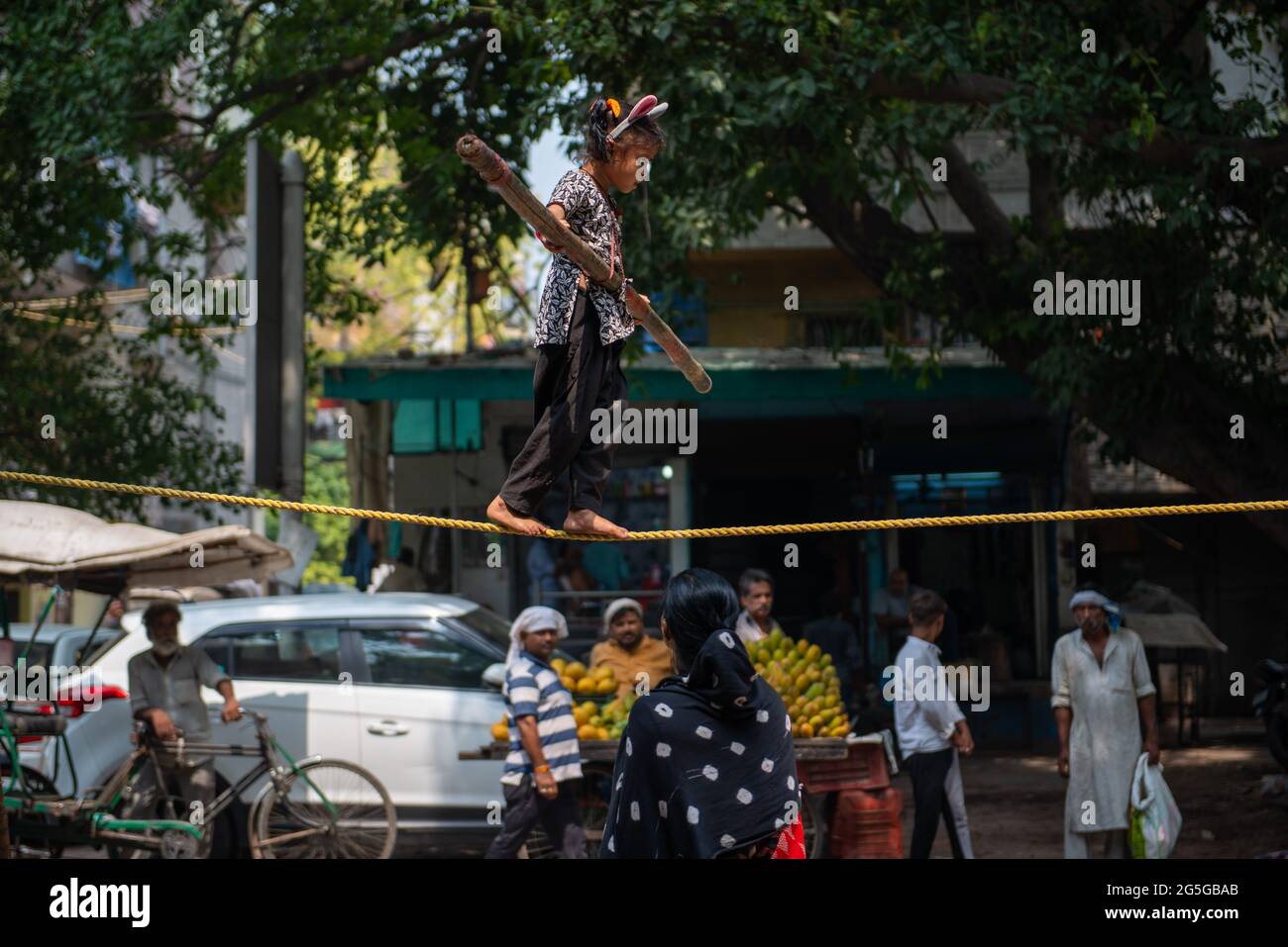 An unidentified Indian girl does street acrobatics by walking on a rope ...