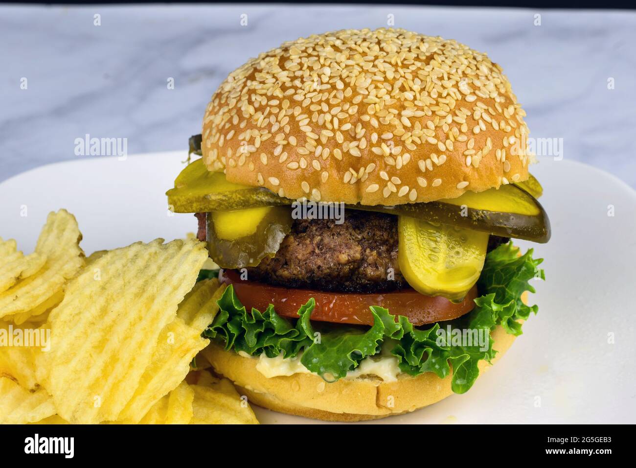 hamburger top with pickle and served with potato chips Stock Photo - Alamy
