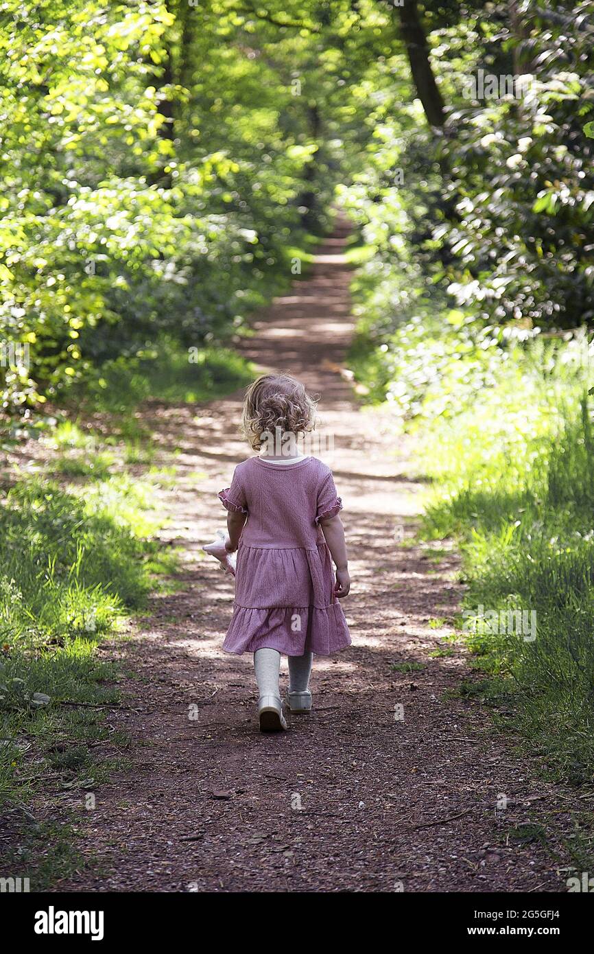 A back view of a cute little caucasian girl walking along the narrow ...