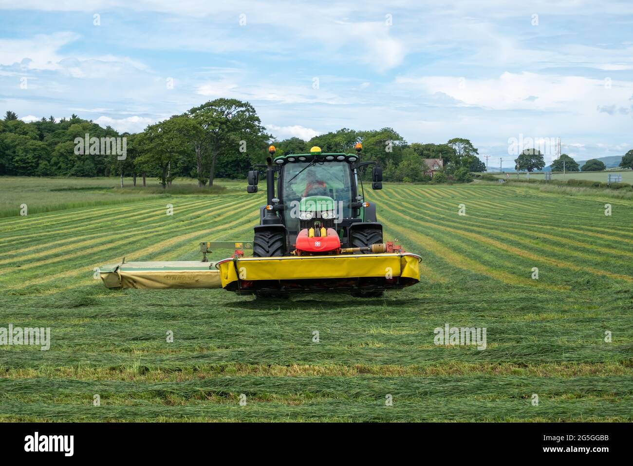 West Kilbride, Scotland, UK. 27th June 2021. A tractor mowing a hay ...