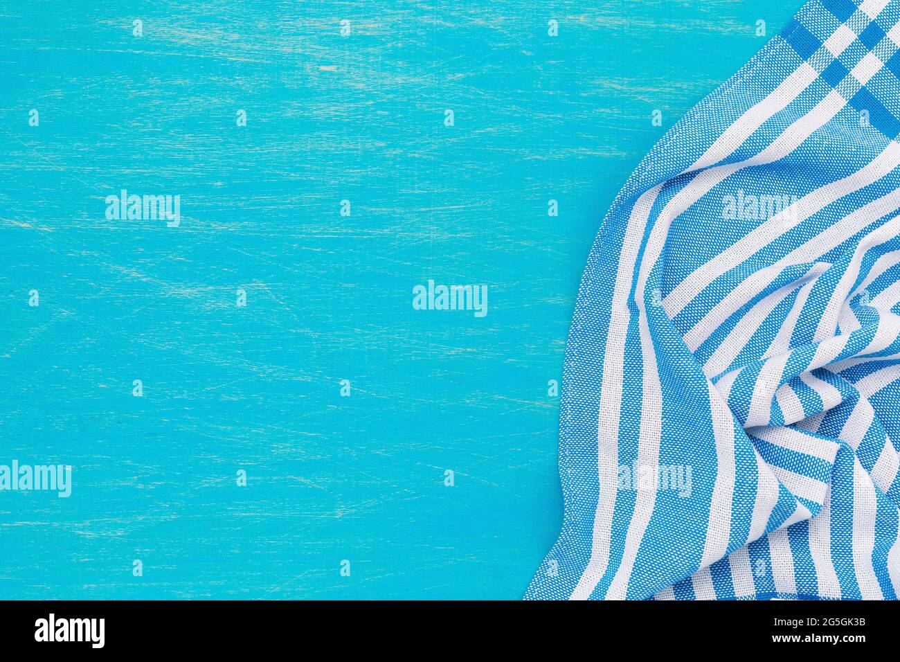 A blue and white napkin on the right side of a light blue wooden table ...