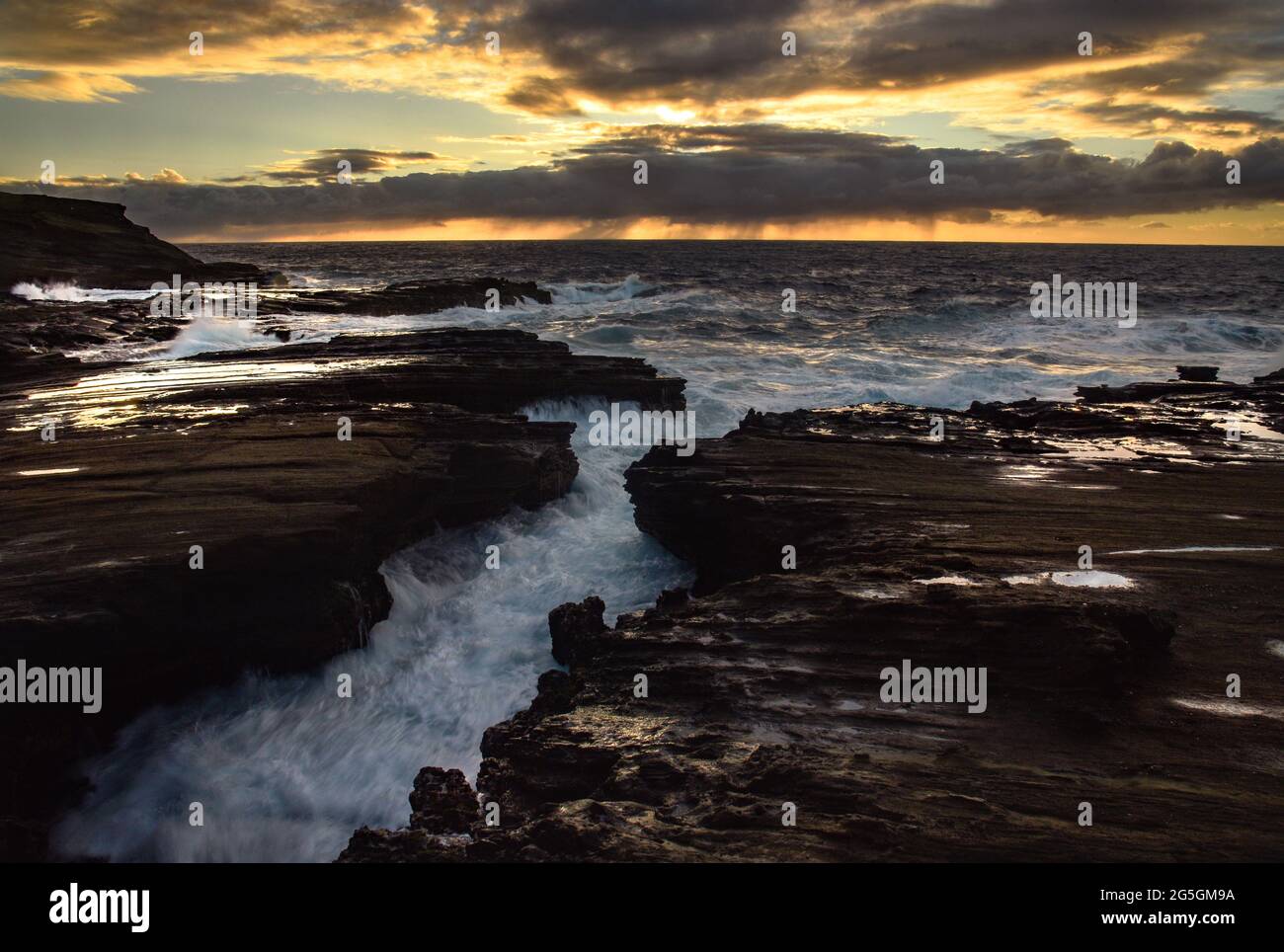 Spectacular sunrise with ocean water crashing and flowing on volcanic ...