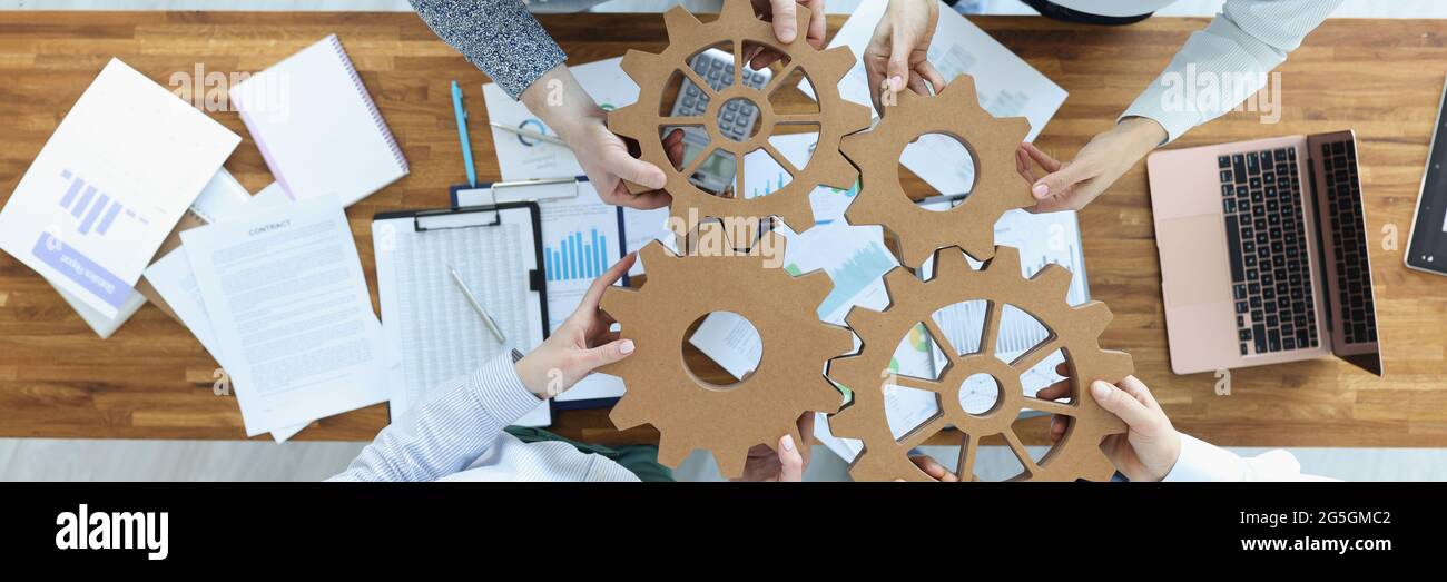 Employees in office connect gears in place Stock Photo - Alamy