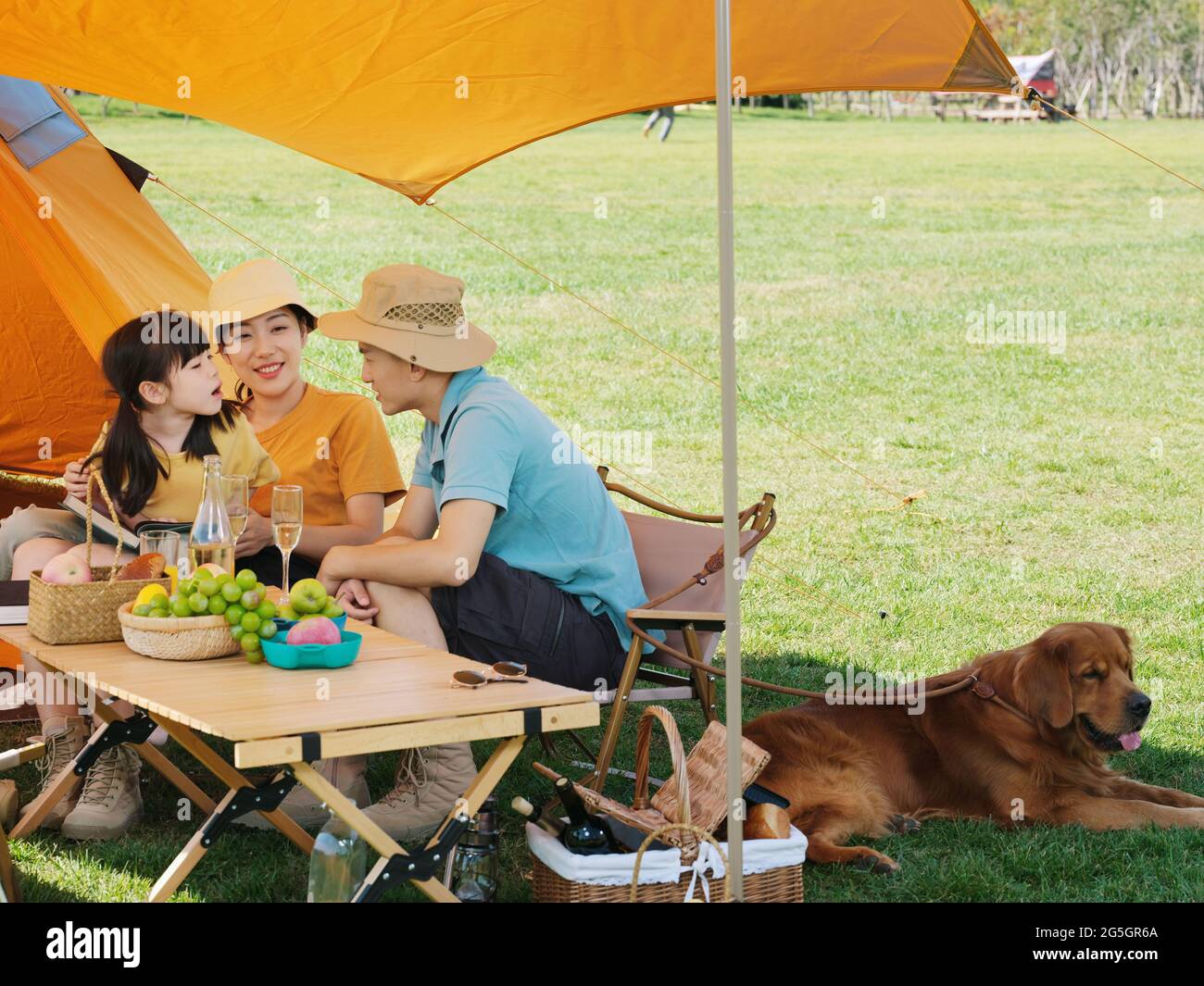 Happy family of three and pet dog reading outside high quality photo ...
