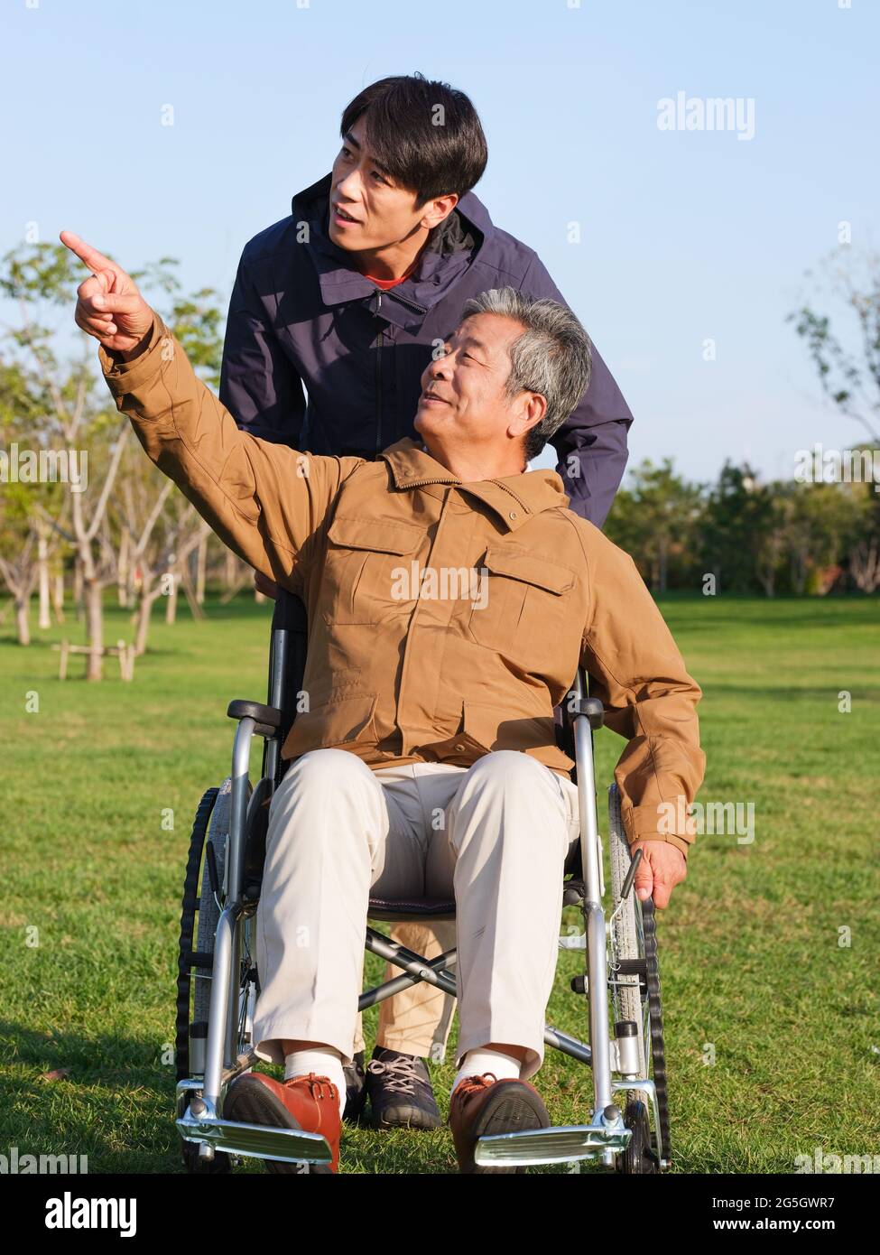 The young man pushed the old man in wheelchair for a walk high quality ...