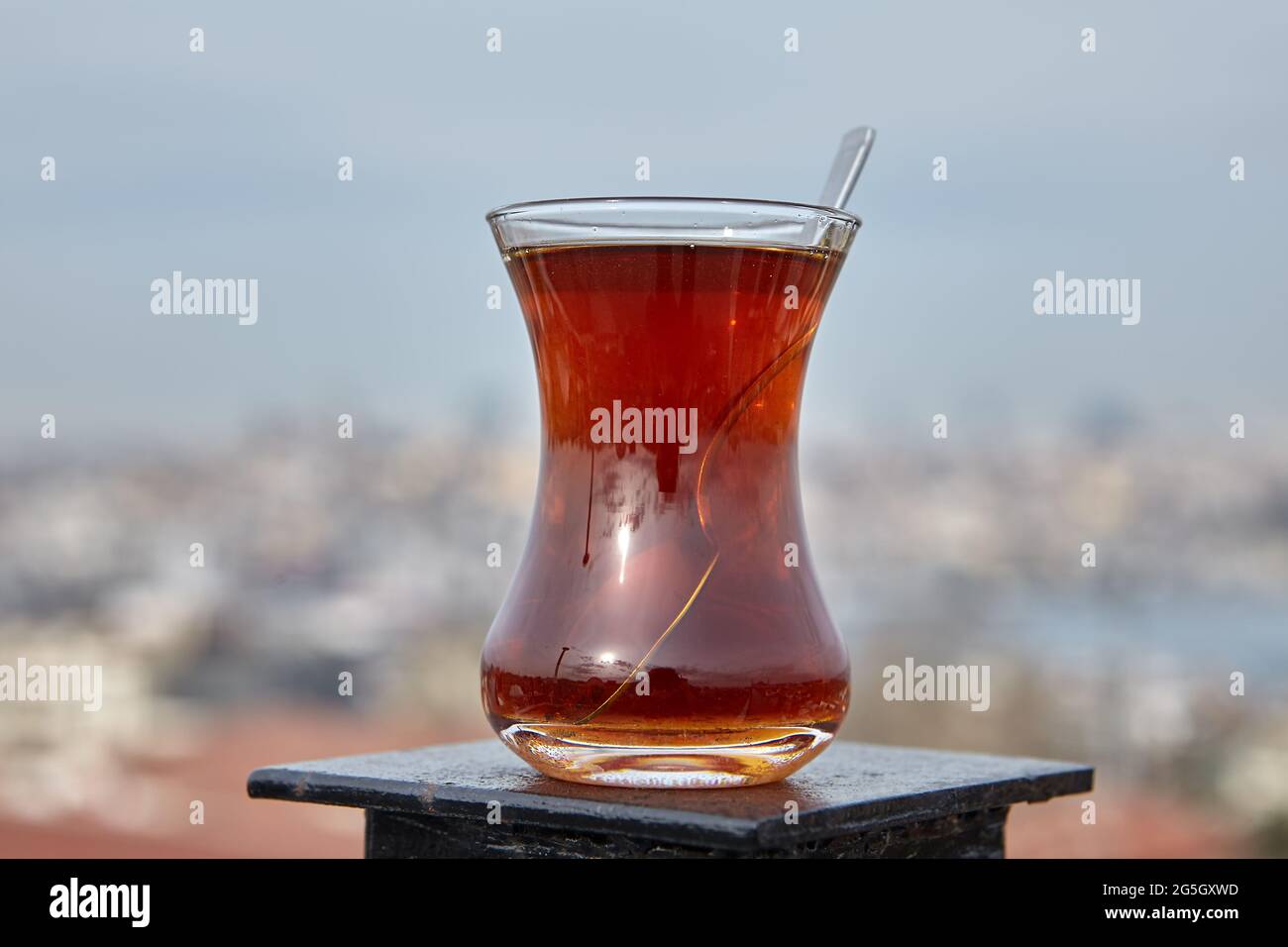 Armudu with Turkish tea stands atop rooftop fence, with defocused view ...