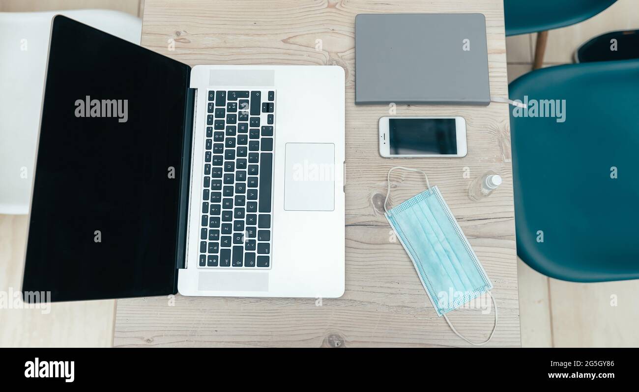 laptop, smartphone and protective mask on the office Desk Stock Photo ...
