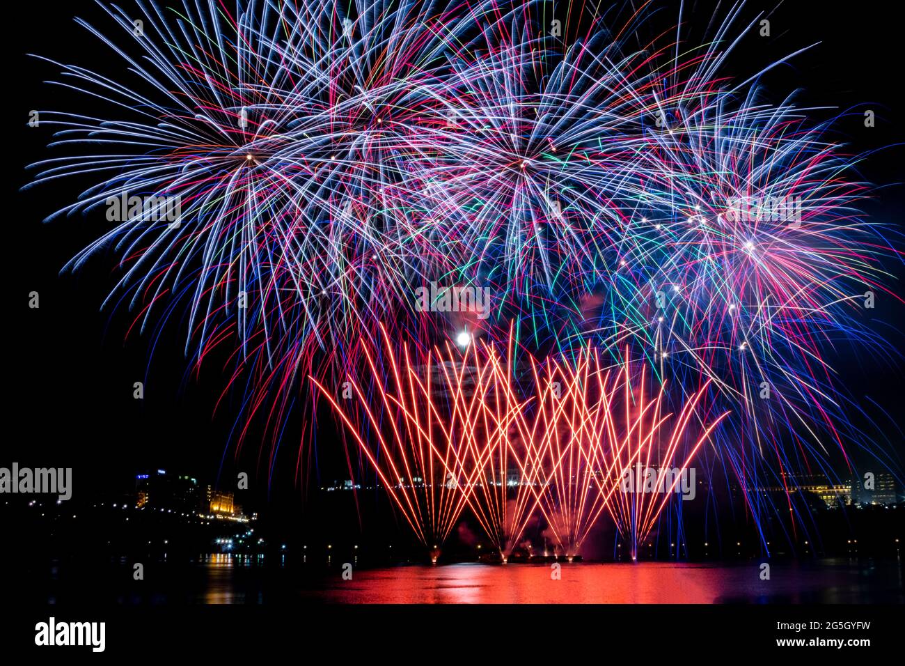 Fireworks over downtown fill the night sky and reflect on the river ...