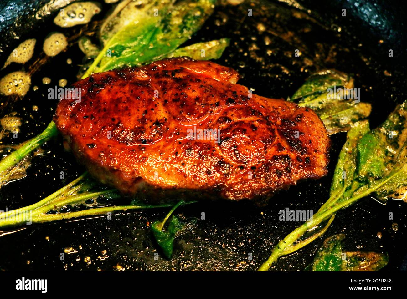 herb marinated pork rib eye cooking with sage in a hot pan Stock Photo ...