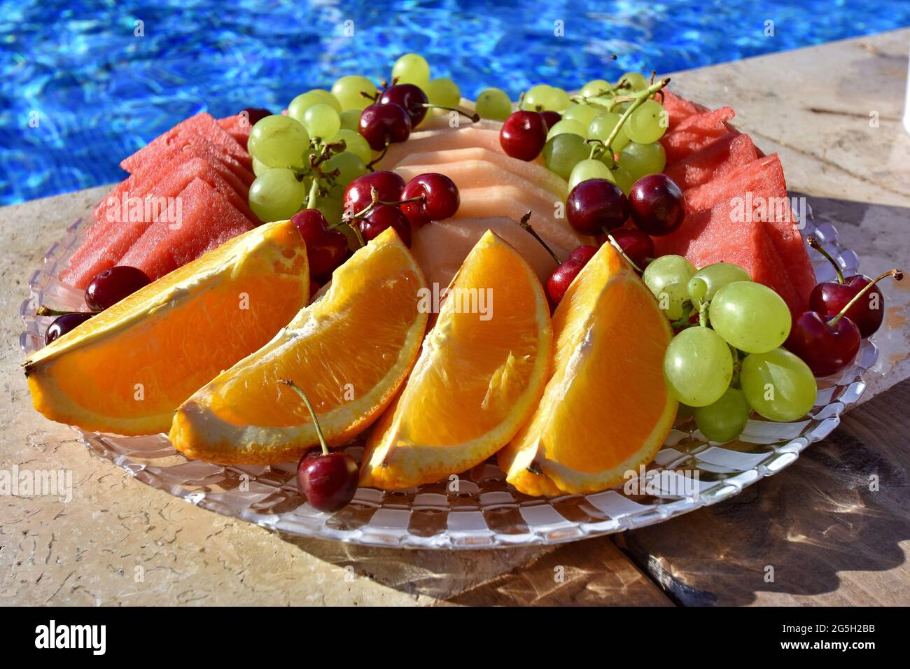 A closeup of grapes, orange, watermelon, and cherries on a plate near ...