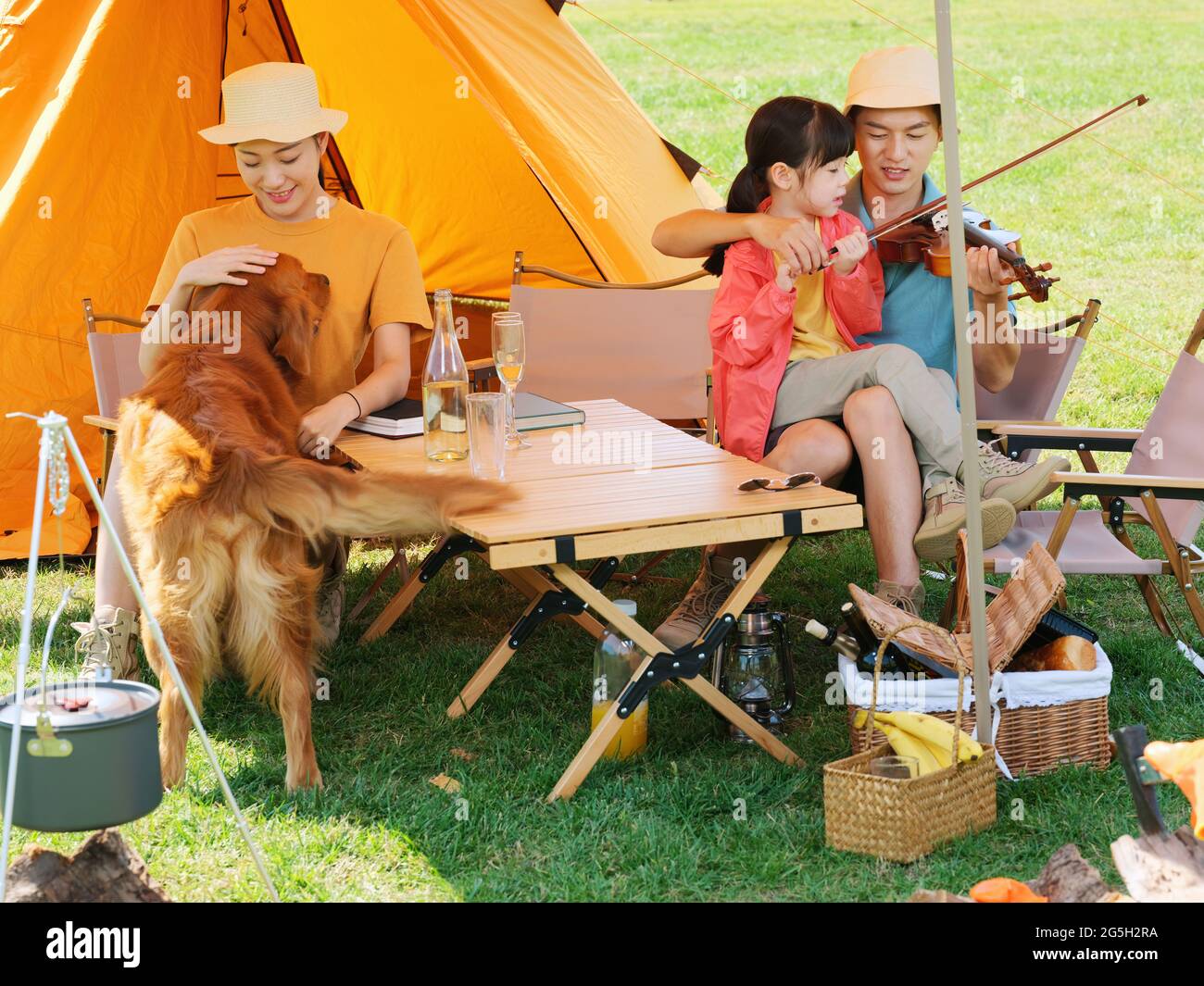 Happy family of three and pet dog playing violin outdoors high quality ...