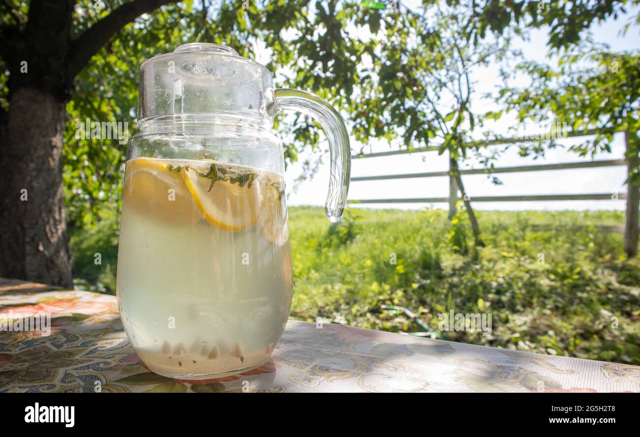 Homemade lemonade made from lemons in a large glass jug on the table in ...