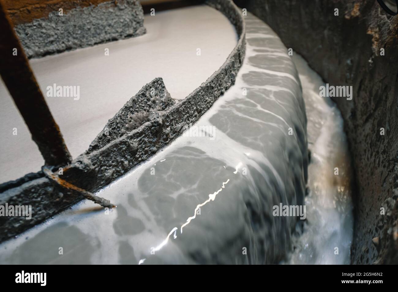 Flotation machine. A stream of gray, dirty liquid flows down from the ...