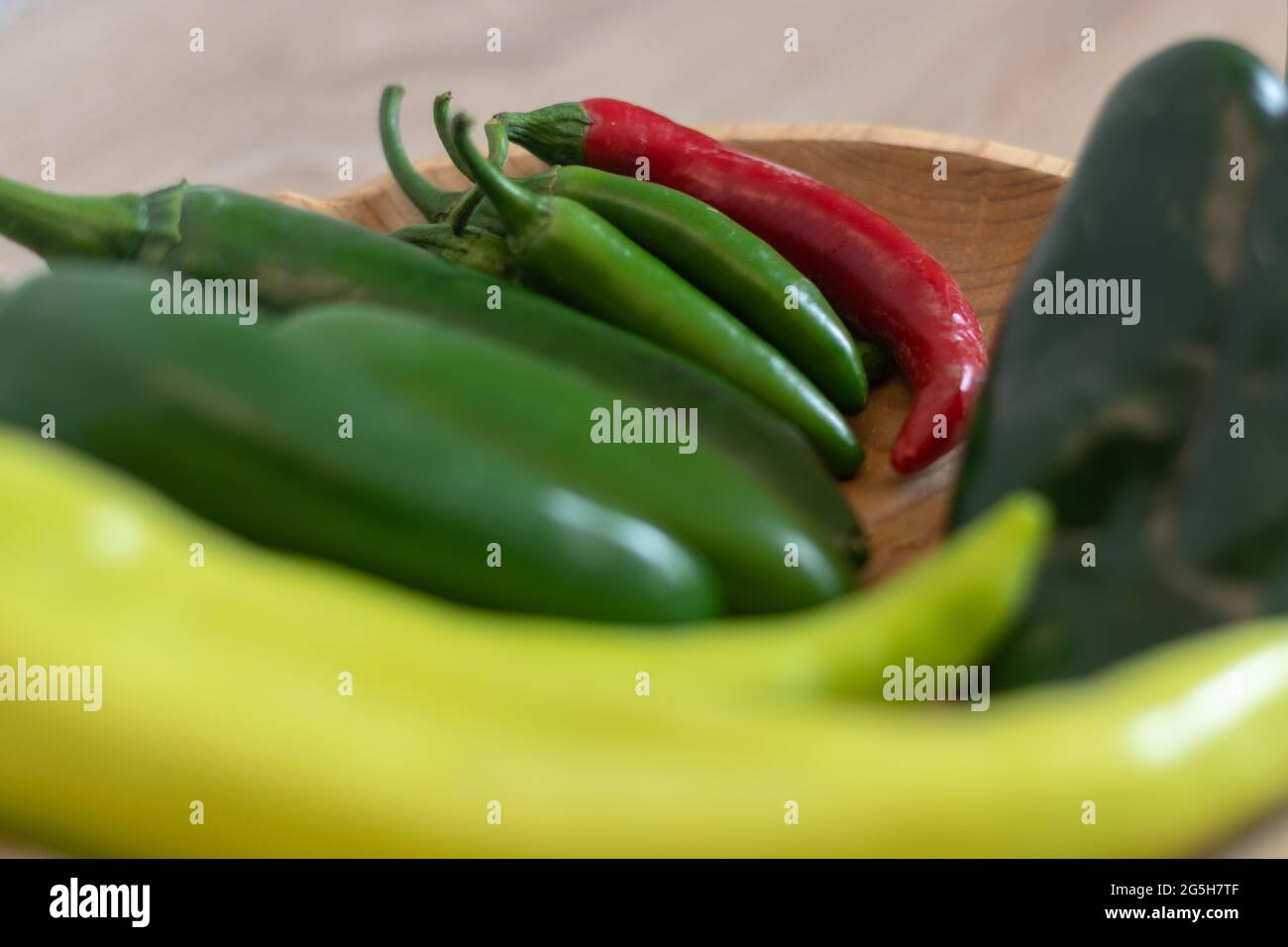 Wooden plate with mix of different peppers. Jalapeño, serrano, poblano ...