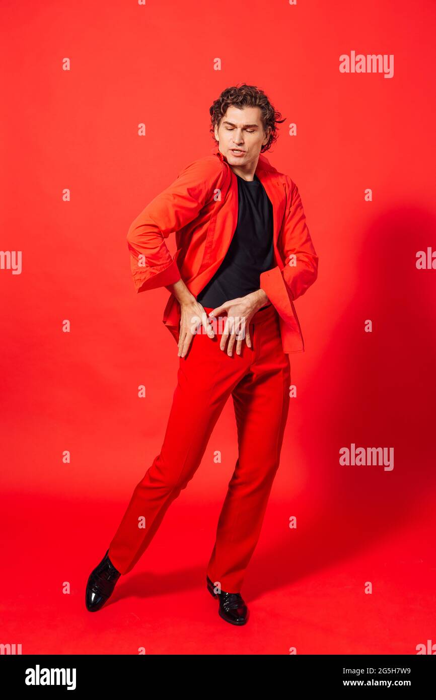 Tall handsome man dressed in red shirt posing on the red background ...