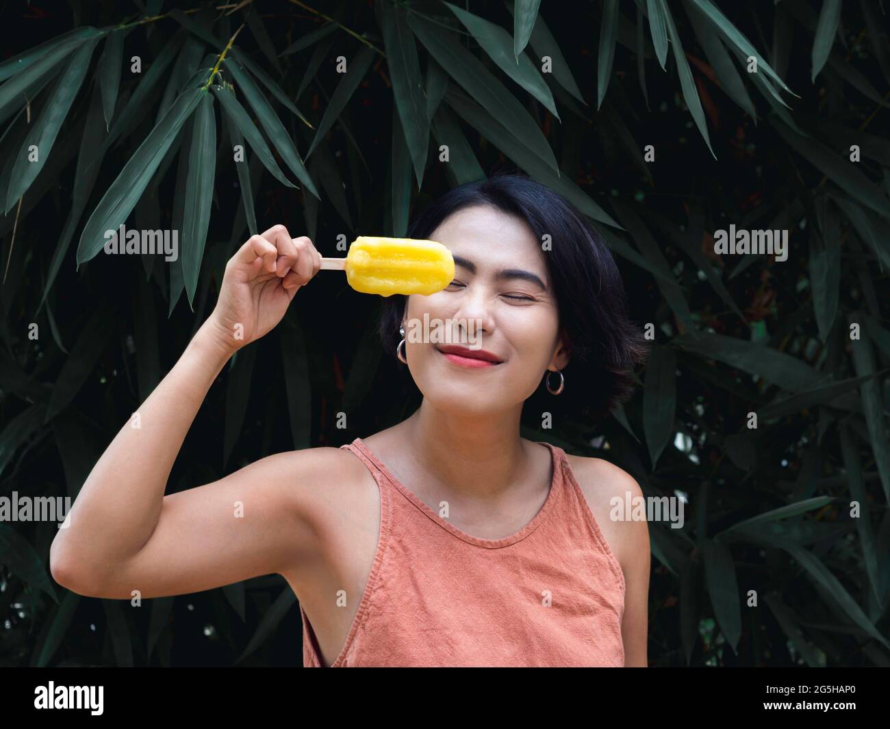 Woman eating popsicles. Happy beautiful Asian woman wearing casual pink ...