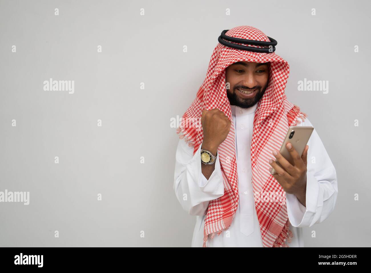 an arabian young man in a turban using a mobile phone happily looking ...