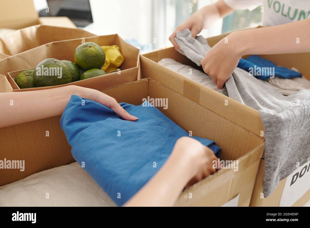Close-up image of people packing tidy clothes and fresh food in ...