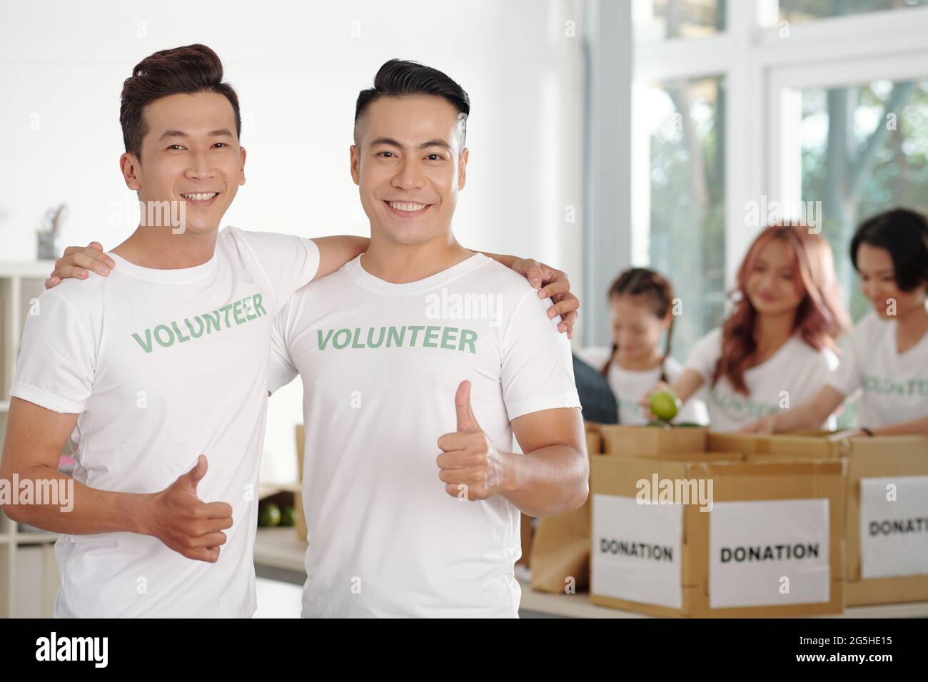 Portrait of positive young charitable foundation volunteers showing ...