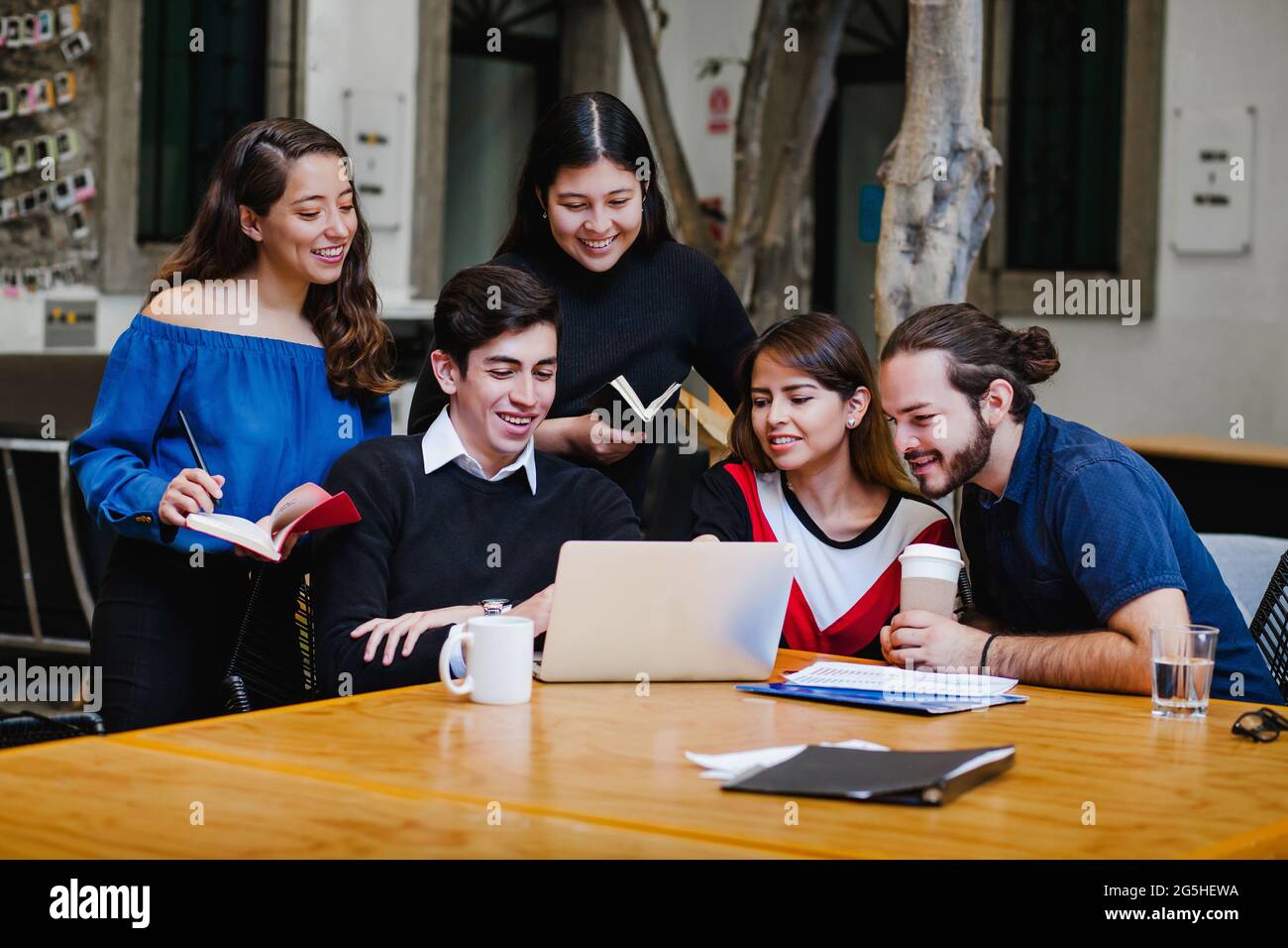 Young latin university students studying with computer in college in ...