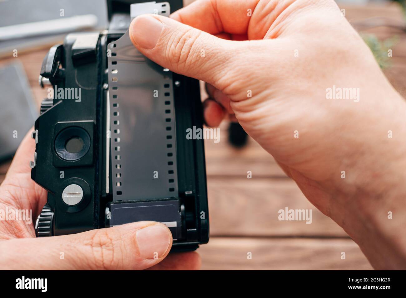 Photographer inserts film into analog camera Stock Photo - Alamy