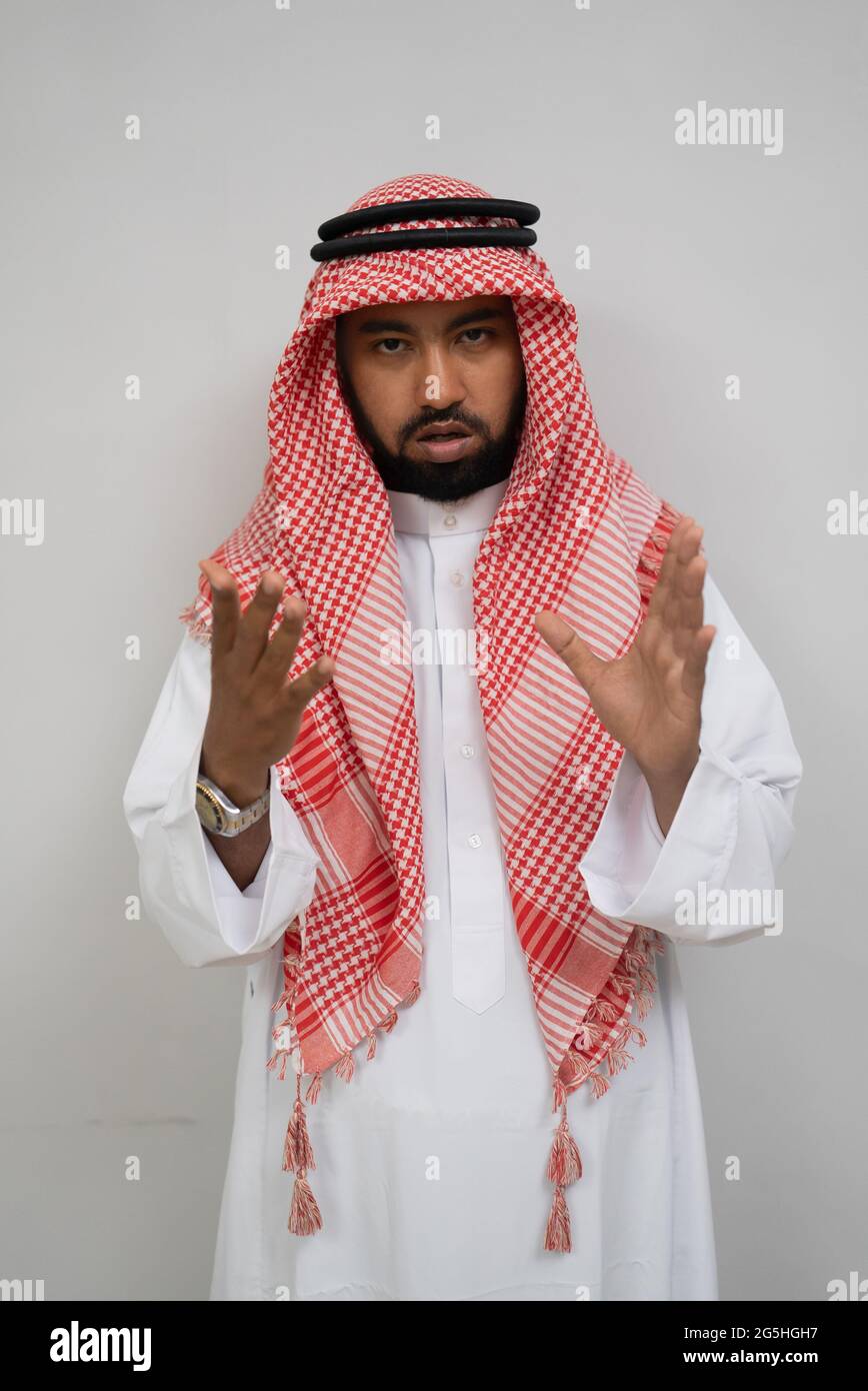 an arabian young man standing looking at the camera with hand gestures ...