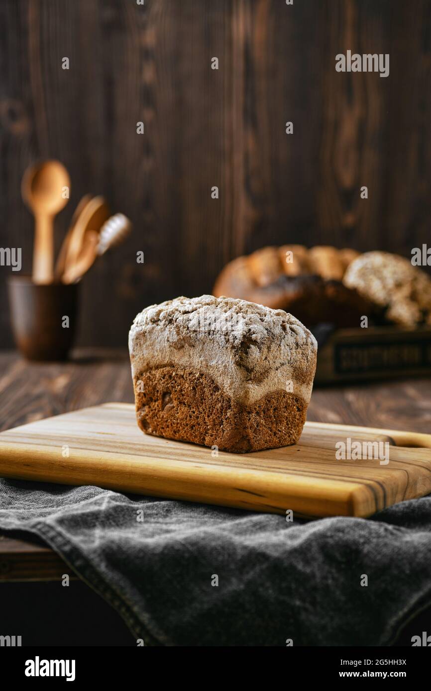 Loaf of artisan rye bread with flour topping on wooden cutting board ...
