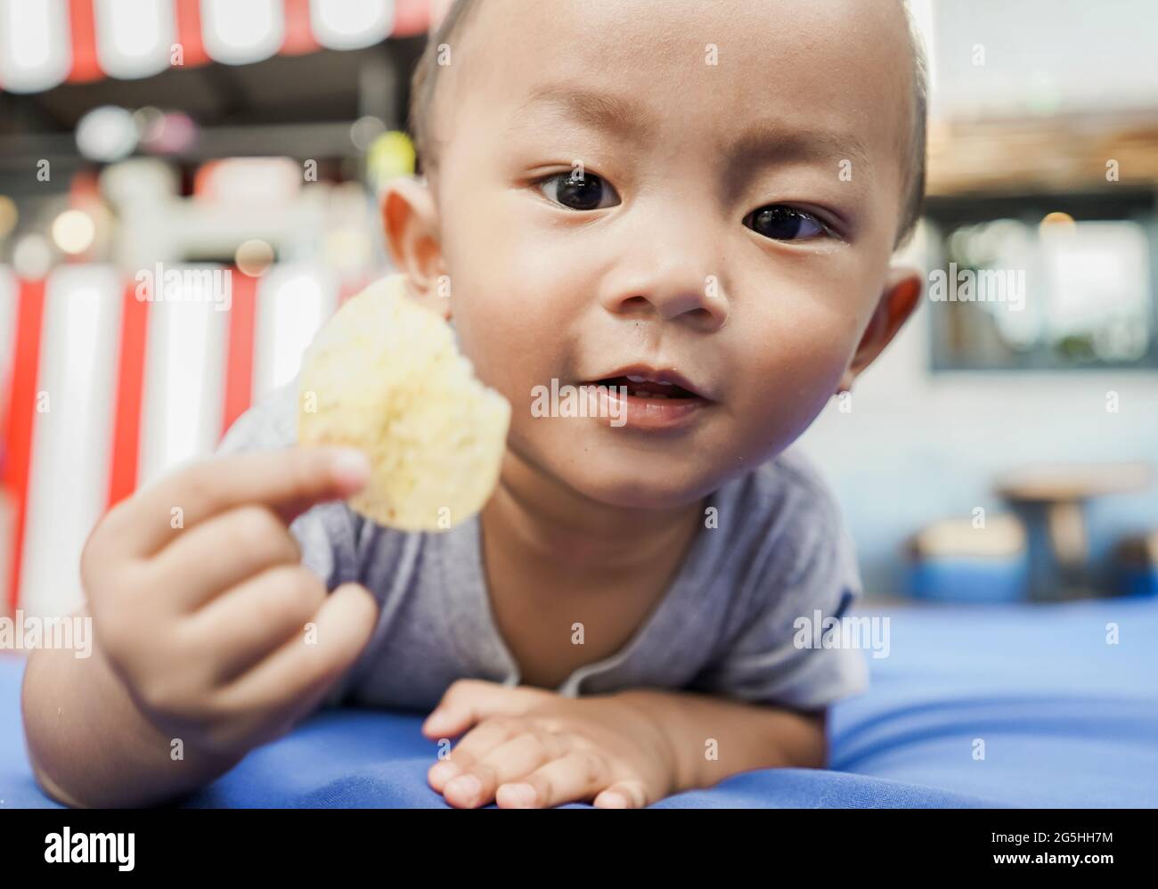 toddler holding a snack while laying Stock Photo - Alamy
