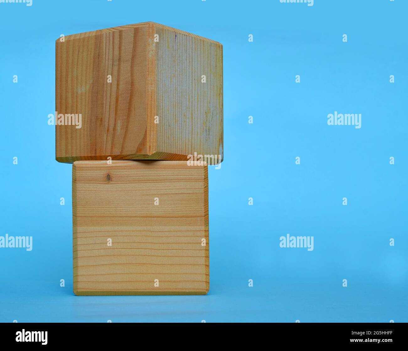 Two wooden cubes stand in a column on a blue background. Mock up ...