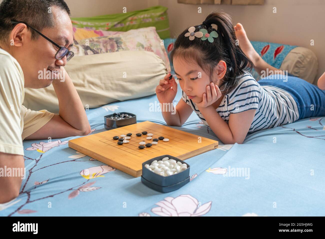 Asian cute child girl playing Go or Chinese traditional board game on ...