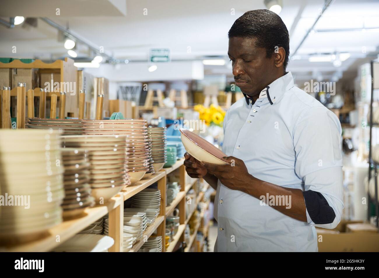Man choosing new crockery in dinnerware store Stock Photo - Alamy