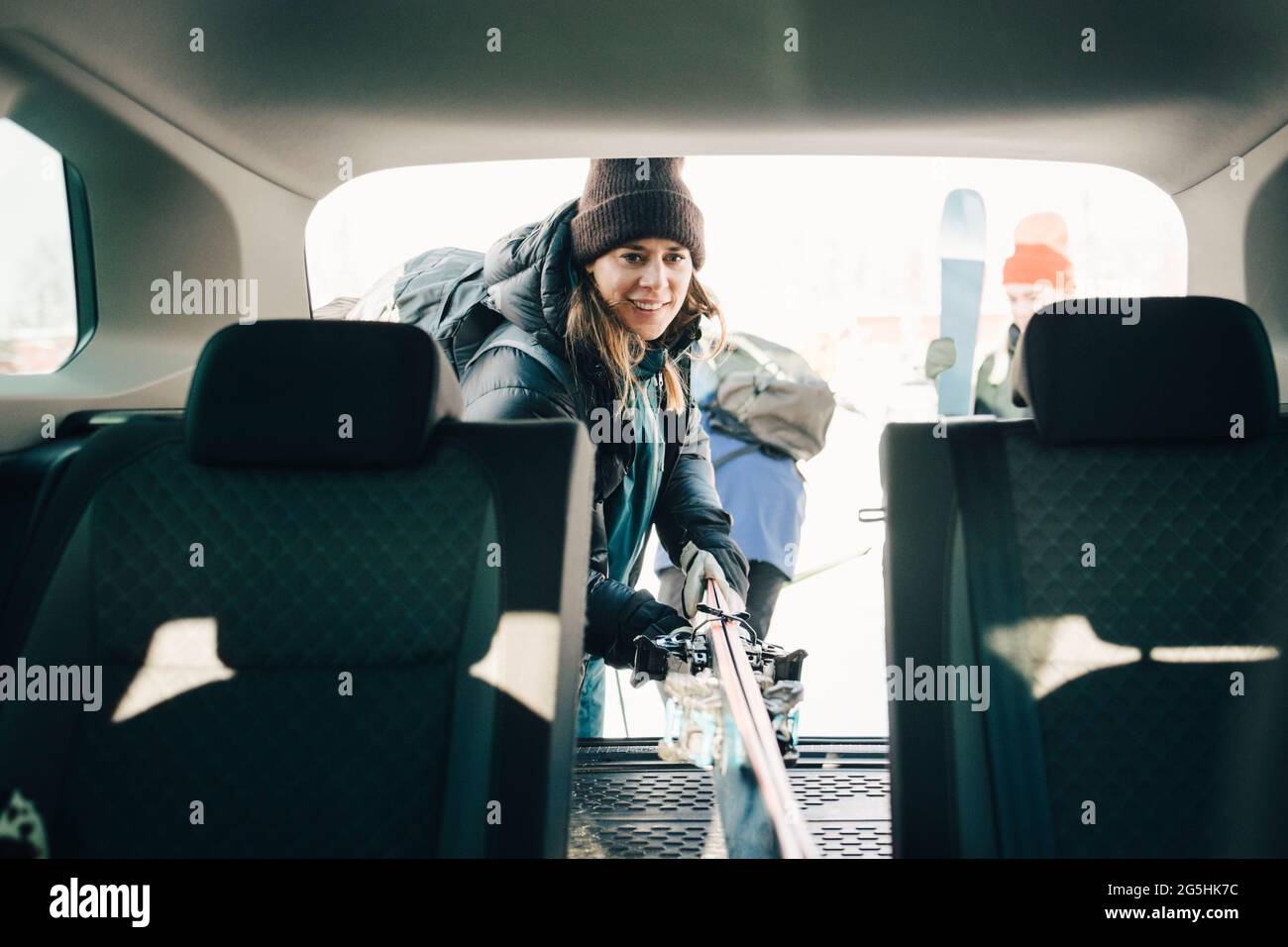 Mid adult woman loading skis in car trunk Stock Photo - Alamy
