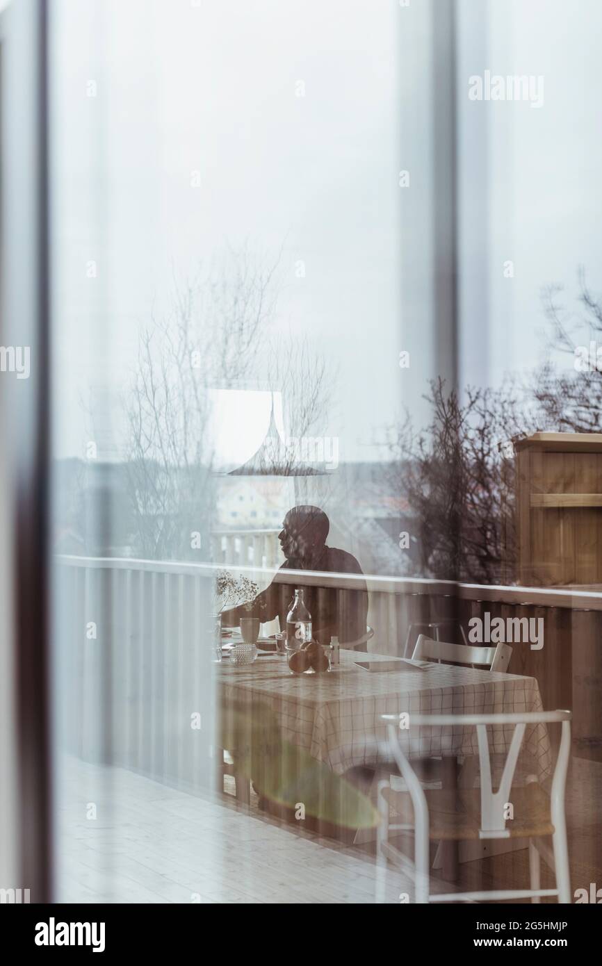 Hispanic man seen through glass window of home Stock Photo - Alamy