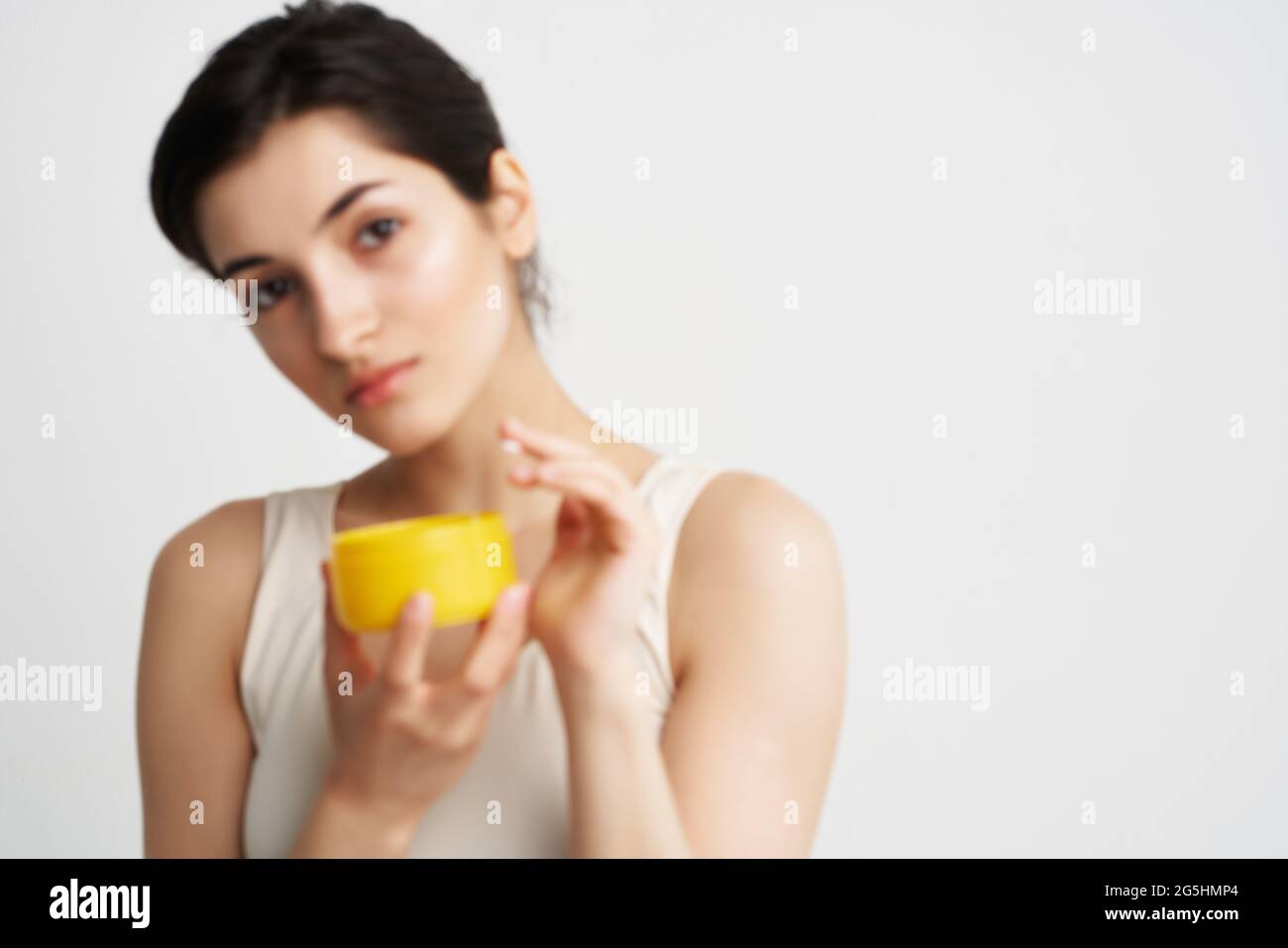 woman with yellow jar of cream cosmetology skin care light background ...