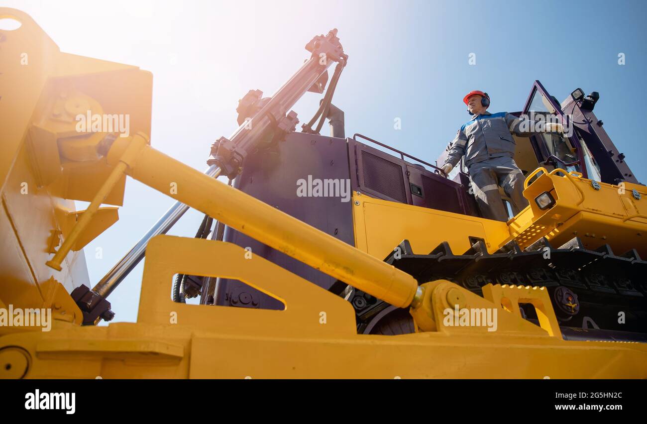 Industrial portrait of working man, excavator driver climbs into cab to ...