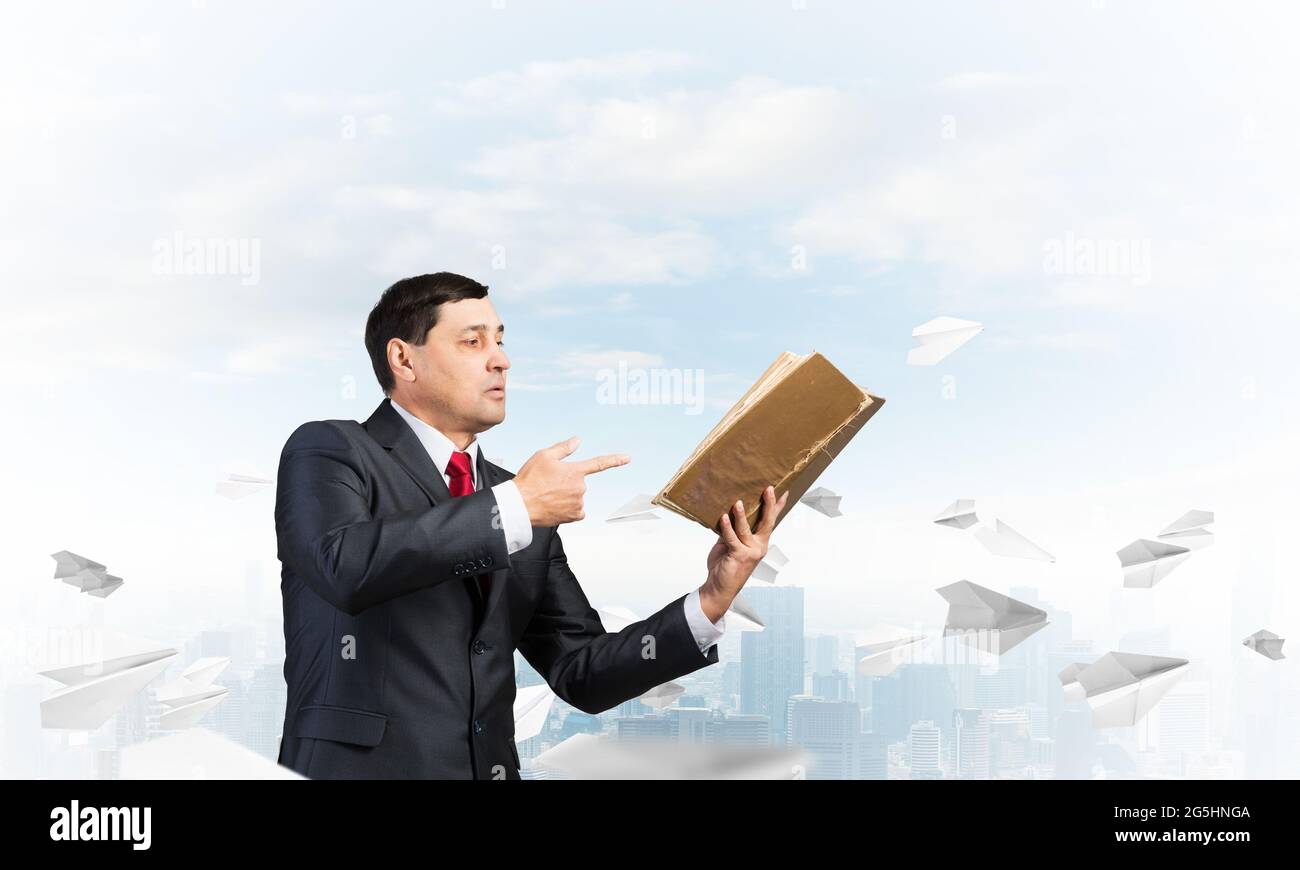 Senior businessman finger pointing into open book Stock Photo - Alamy