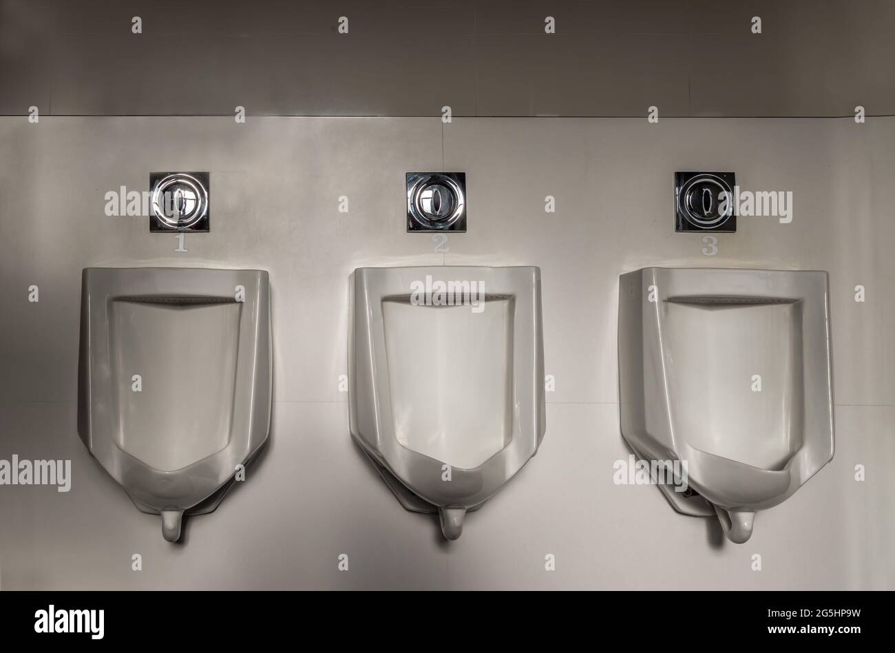 Closeup of three white seperated urinals and automatic infrared ...