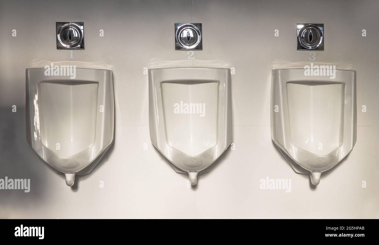 Closeup of three white seperated urinals and automatic infrared ...