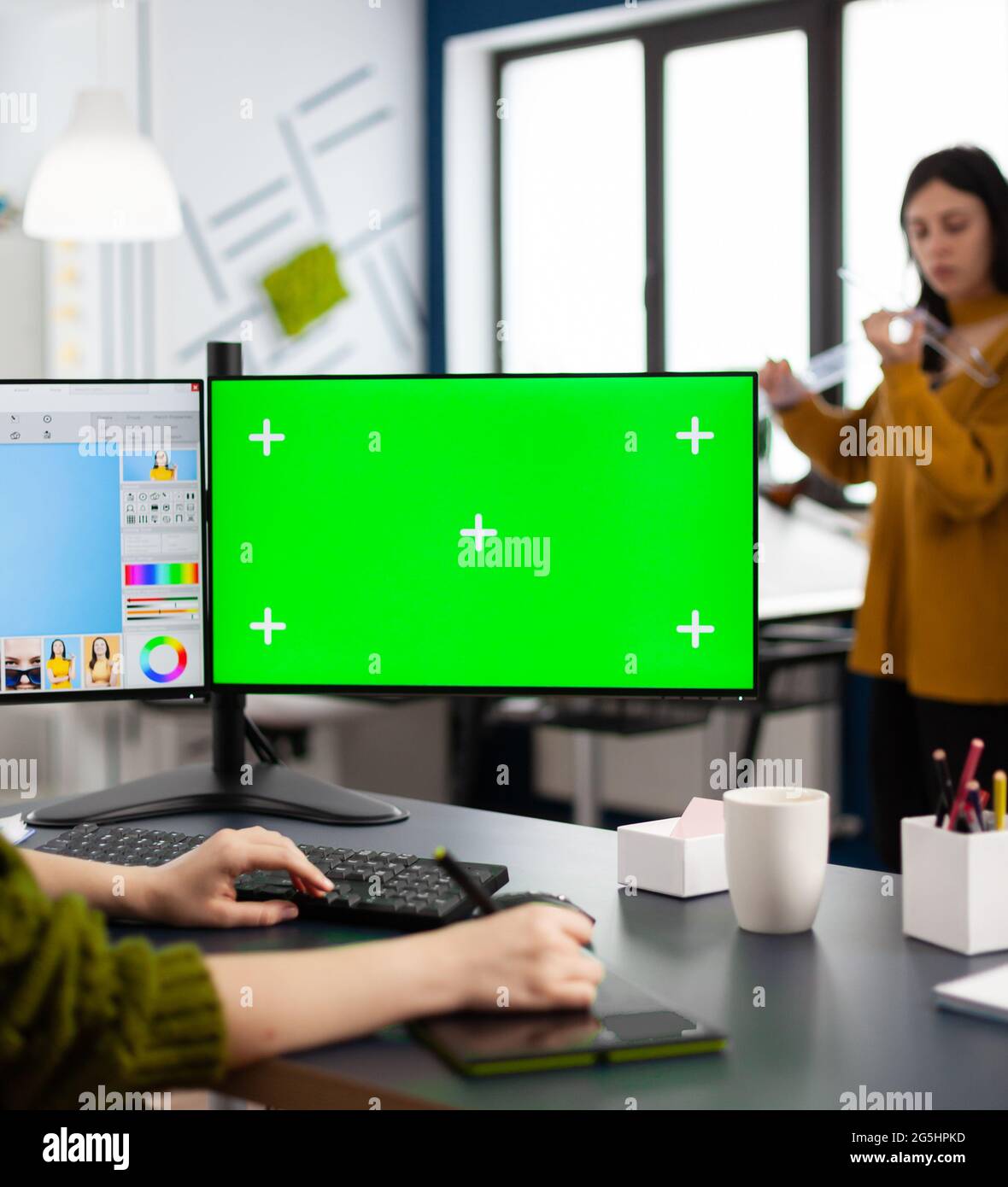 Photographer working on green mock-up screen, computer with chroma key ...