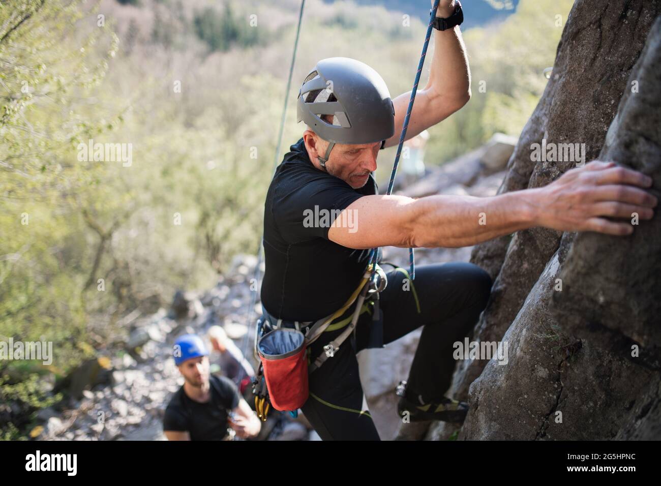 Senior man with instructor climbing rocks outdoors in nature, active ...
