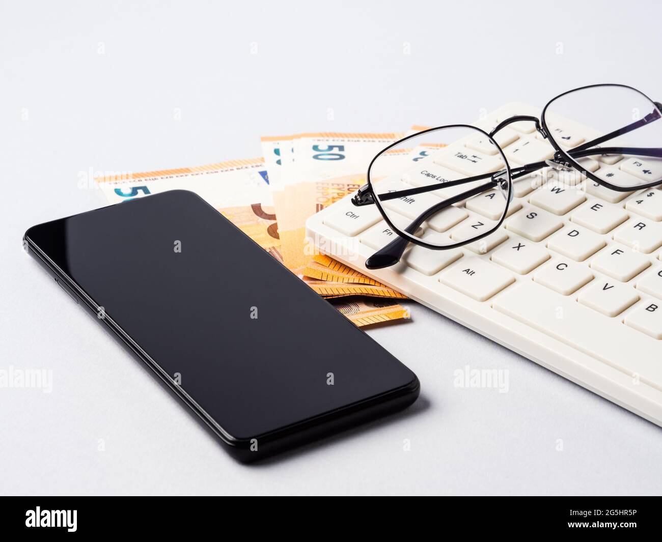 Euro money banknotes, keyboard, smartphone and glasses, online banking ...