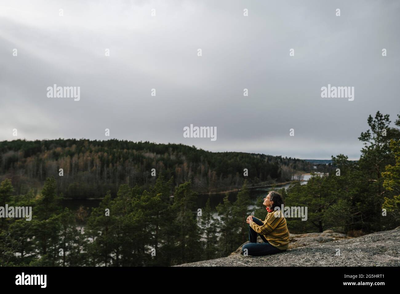 Mature female explorer sitting on mountain against sky Stock Photo - Alamy