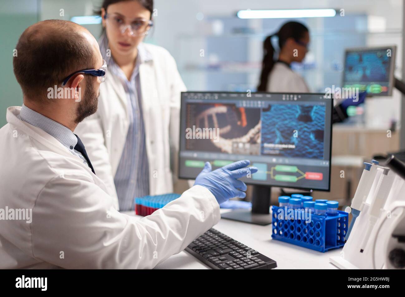 Medical team scientist conducting DNA experiments looking in computer ...