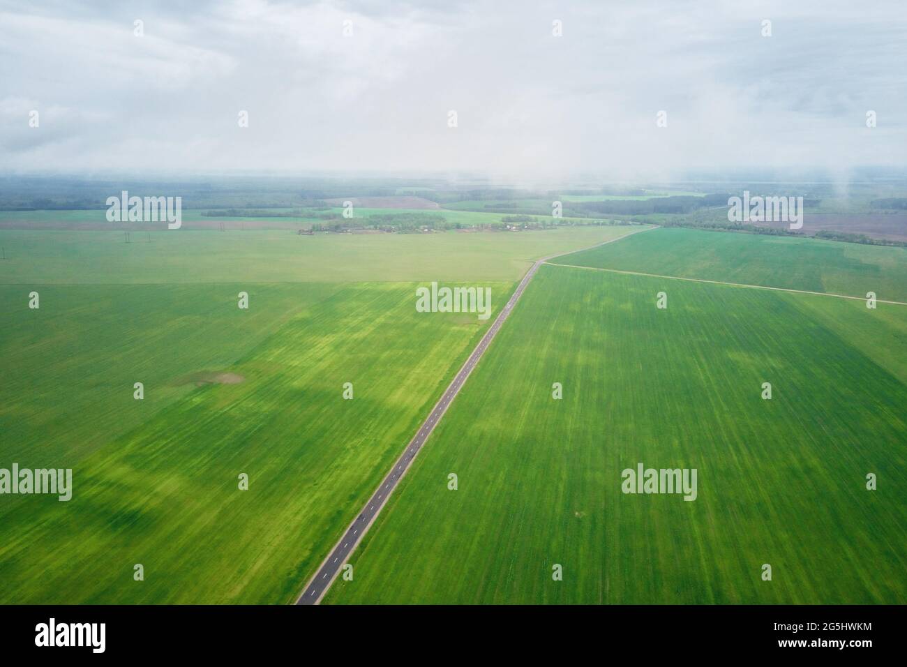 Flight through the clouds. Aerial view of car road near green field ...